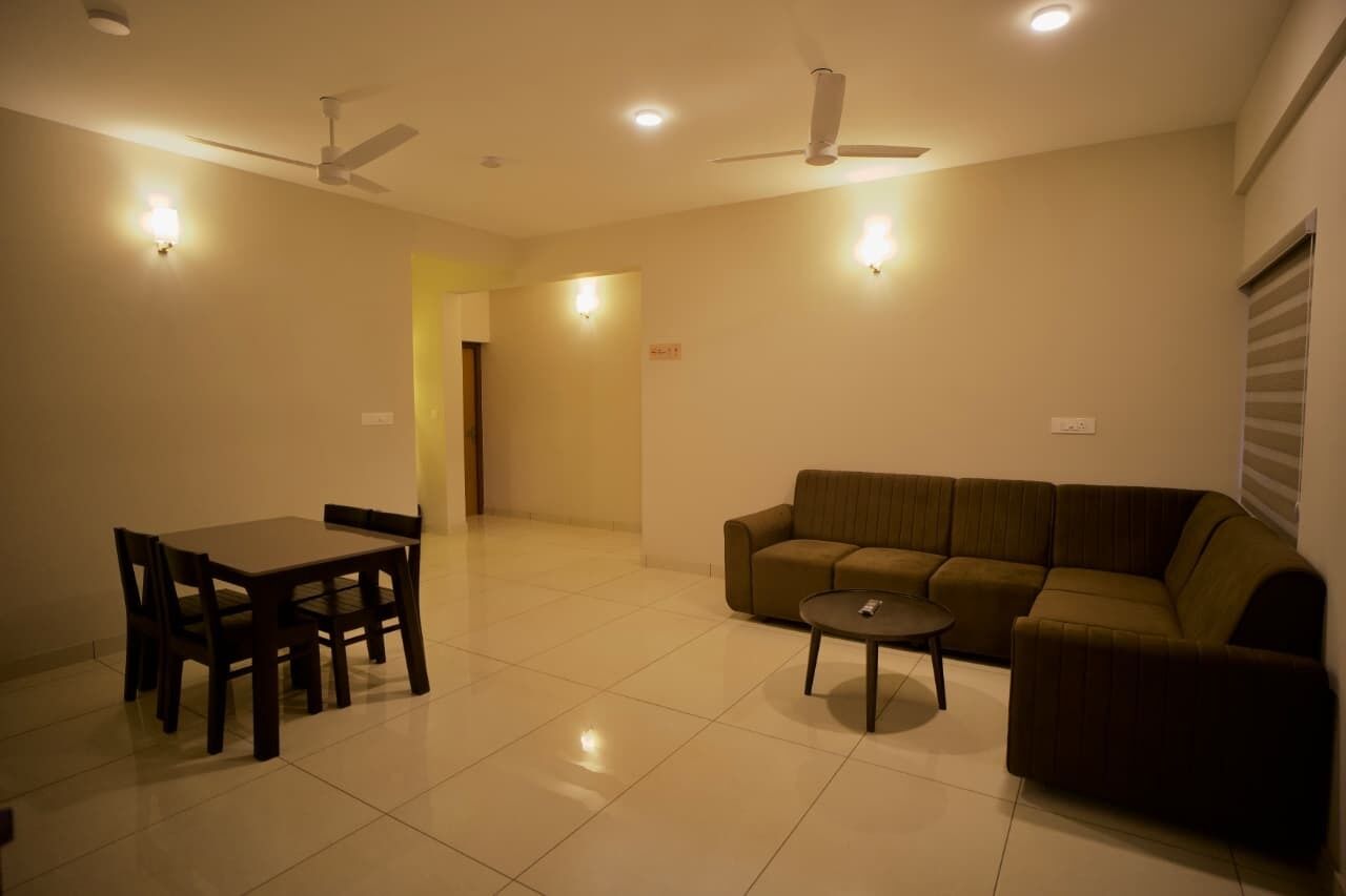 Uma sala de estar com sofá, mesa de centro, mesa de jantar com cadeiras e ventiladores de teto.