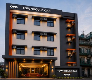 Hotel Townhouse Oak, de vários andares, com fachada moderna, diversas janelas e área de recepção com assentos.