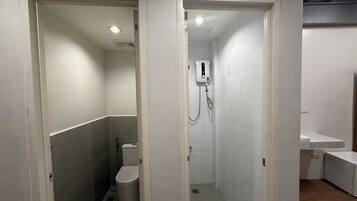 Casa de banho compacta com sanita, zona de duche e lavatório.