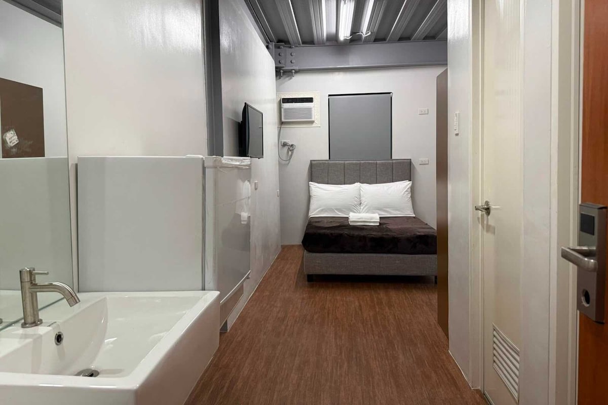 Quarto de hotel com banheiro, cama e televisão.