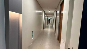 Um corredor comprido e estreito com portas de ambos os lados, dando acesso a quartos individuais.