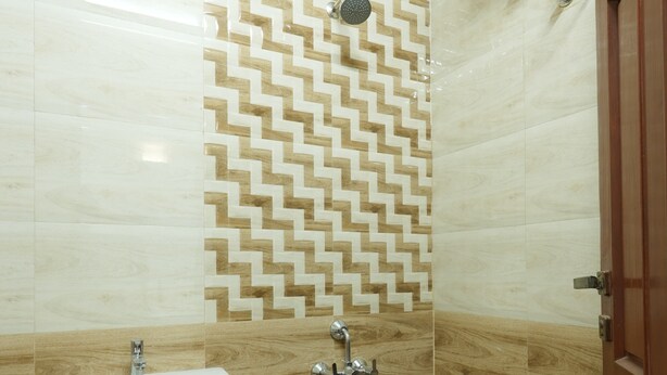 Casa de banho com lavatório, chuveiro e parede com padrão herringbone.