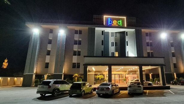 Um hotel com fachada moderna, vários espaços de estacionamento e uma placa de destaque.