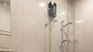 Casa de banho com sanita, chuveiro e zona de duche com parede de vidro.