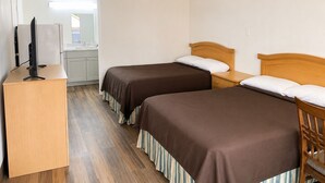 Quarto de hotel com duas camas, uma escrivaninha e uma cozinha compacta.
