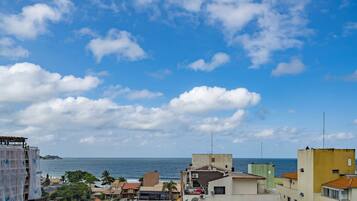 Uma área urbana costeira com edifícios, céu claro e o mar ao fundo.