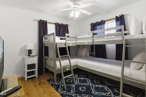 Quarto com beliche, um abajur sobre uma mesinha de cabeceira e um tapete estampado.