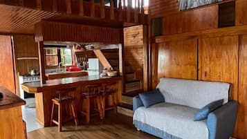 Interior em madeira com sofá, cozinha e mezanino.