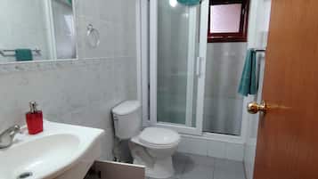 Casa de banho com lavatório, sanita e zona de duche.