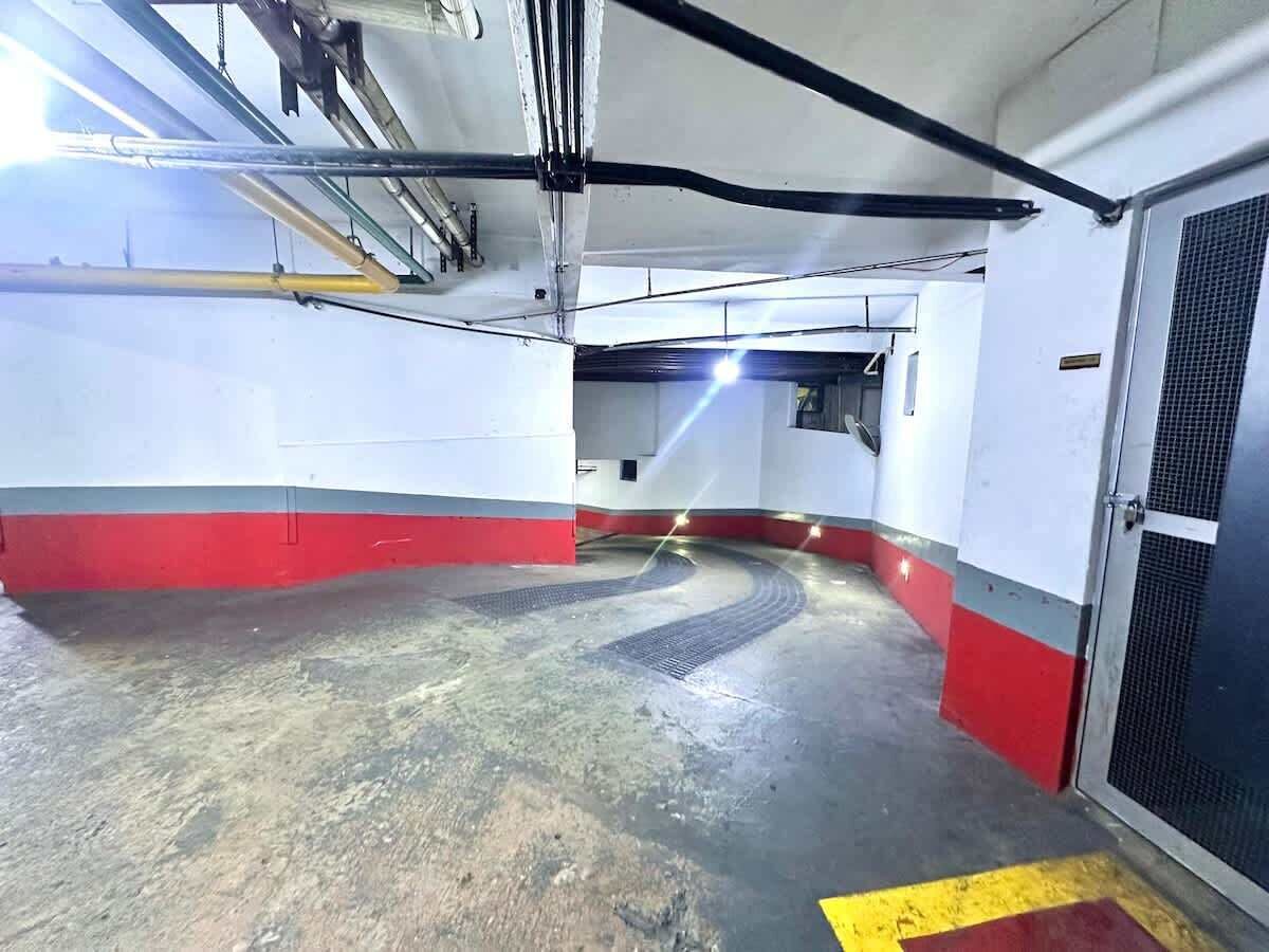 Uma garagem de estacionamento com piso de concreto, paredes vermelhas e brancas e um sistema de ventilação.