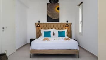 Quarto com uma cama grande, duas luminárias de cabeceira, uma obra de arte na parede e uma janela.