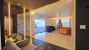 Um hall de hotel moderno com balcão de recepção, área de estar e um pinheiro de Natal.