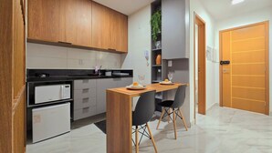 Uma cozinha compacta com eletrodomésticos modernos, uma área de refeições com duas cadeiras e uma porta de madeira.