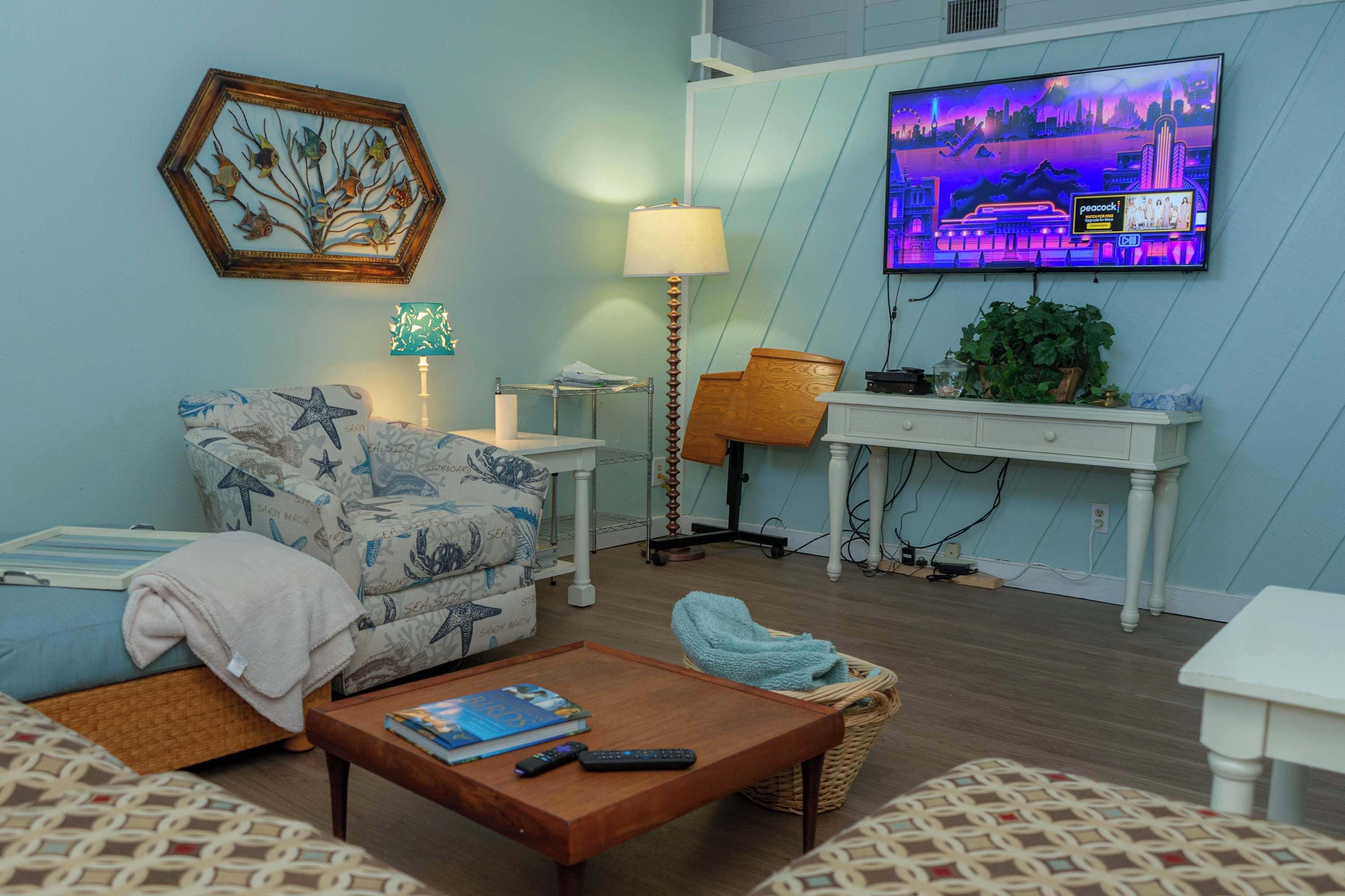 Uma sala de estar com sofá, mesa de centro, televisão, abajur e planta.