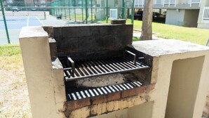 Uma churrasqueira portátil com grelha de metal, apoiada sobre uma base de concreto.