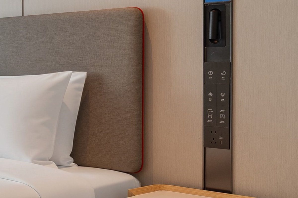 Cama com cabeceira cinza e painel de controle com símbolos.