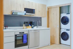 Uma cozinha compacta com micro-ondas, cafeteira e máquina de lavar integrada.