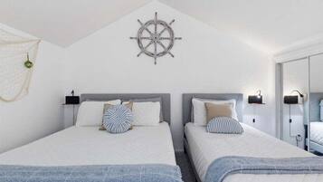 Quarto com duas camas, um adorno de leme e uma pequena decoração pendente.