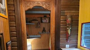 Um corredor estreito com uma porta de madeira que dá para um quarto com janela.