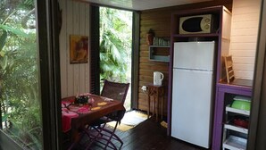 Uma cozinha compacta com geladeira, micro-ondas e prateleiras de madeira.