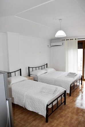 Quarto com duas camas, ventoinha no teto e ar condicionado.