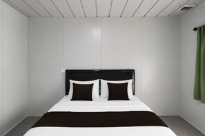 Quarto de hotel com uma cama, cabeceira e cortina verde.