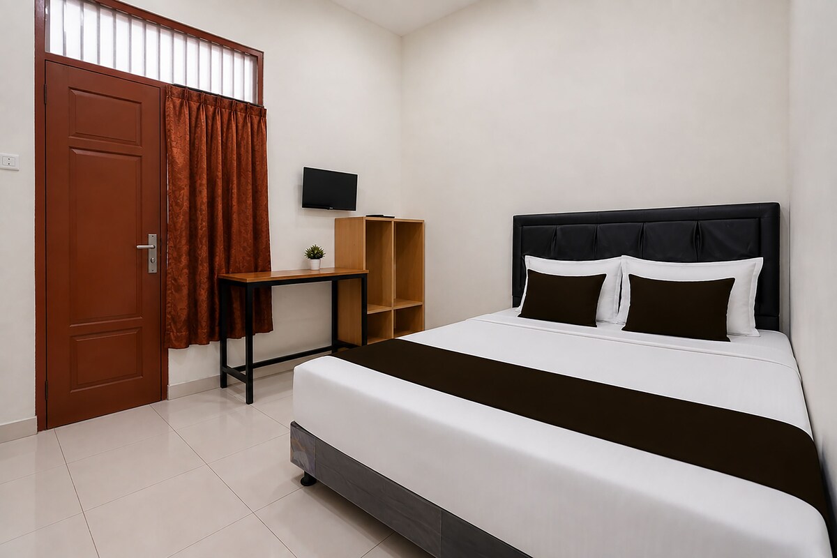 Quarto com cama, escrivaninha, televisão e guarda-roupa.