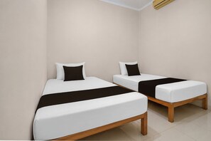 Quarto com duas camas de solteiro, cada uma com colchão branco e roupa de cama preta.