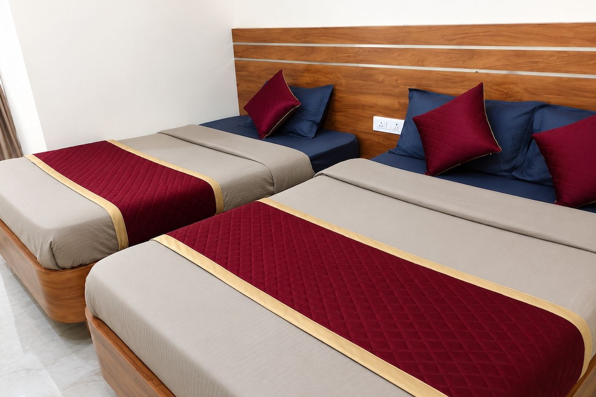Duas camas com cabeceiras de madeira, roupa de cama bege e vermelha, e almofadas combinando.