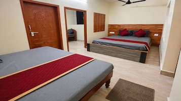 Quarto de hotel com duas camas, porta de madeira, ventilador de teto e espelho.