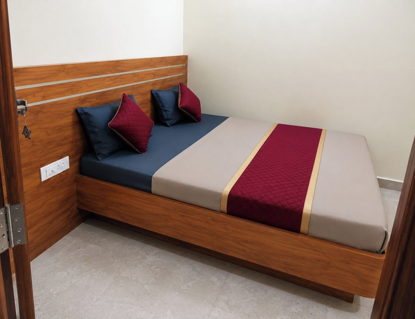 Uma cama de solteiro com cabeceira de madeira, colchão bege e duas almofadas.