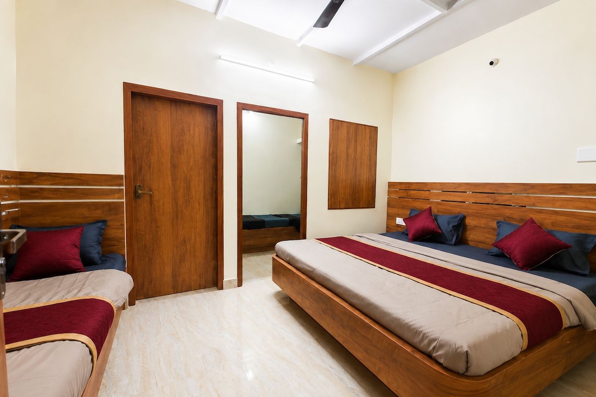 Quarto de hotel com uma cama grande, uma cama menor e um guarda-roupa.