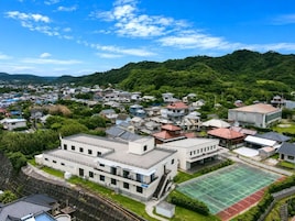 Zona residencial com casas modernas, um edifício grande com telhado plano e um campo esportivo.