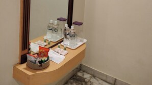 Casa de banho com toucador de madeira, espelho e artigos de higiene pessoal.