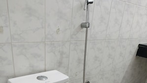 Casa de banho com sanita, chuveiro e lavatório.