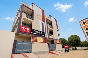 Um edifício moderno com uma placa indicando 'OYO Collection' e uma placa indicando 'Reserve no Aplicativo OYO'.
