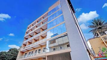 Um edifício de vários andares com design arquitetônico moderno, com varandas e grandes janelas.