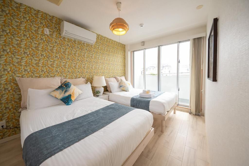 Quarto de hotel com duas camas, uma janela grande e uma varanda.
