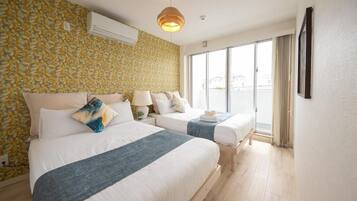 Quarto de hotel com duas camas, uma janela grande e uma varanda.