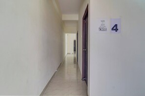 Um corredor com piso ladrilhado, uma porta com a placa de número 4 e uma placa indicando 'proibido fumar, proibido beber' na parede.
