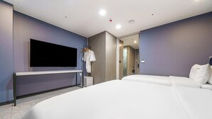 Quarto de hotel moderno com uma cama grande, televisão de tela plana e chuveiro amplo.