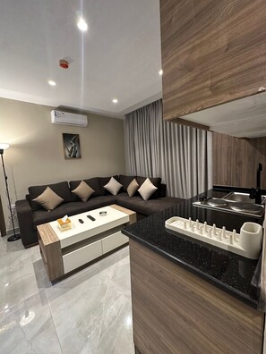 Uma sala de estar moderna com um sofá, uma mesa de centro e uma área de cozinha com fogão.