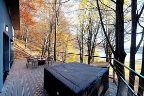 Um terraço com mobiliário de exterior, área de estar coberta e vista para árvores e um corpo de água.