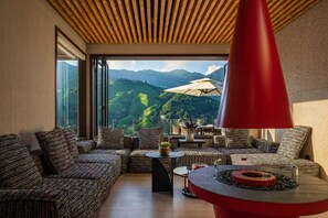 Uma área de estar moderna com vista para colinas e montanhas verdes.