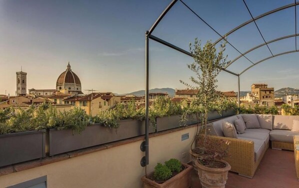 Terraço no terraço com vista para edifícios históricos, incluindo uma cúpula e um campanário.