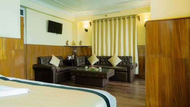 Quarto de hotel com uma cama, um sofá, uma mesa de centro e um guarda-roupa de madeira.
