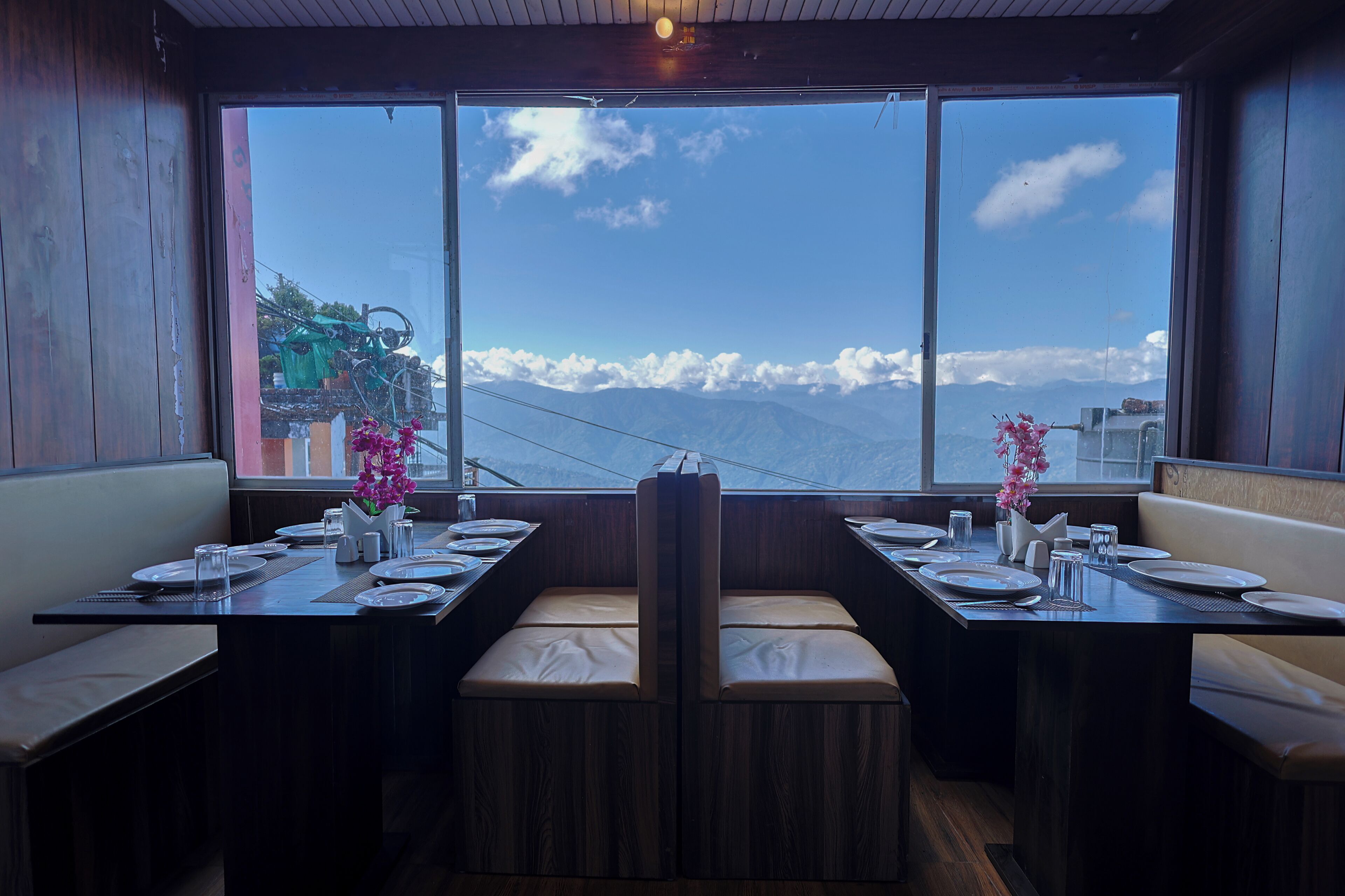 Um restaurante com vista para montanhas através de grandes janelas.