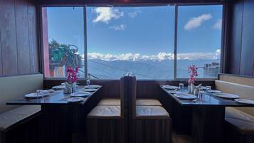 Um restaurante com vista para montanhas através de grandes janelas.
