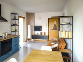 Uma cozinha moderna com armários azuis, uma mesa de jantar de madeira e uma TV fixada na parede.