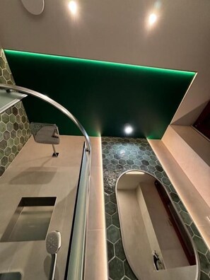 Um banheiro moderno com parede verde decorativa, banheira e área de chuveiro.